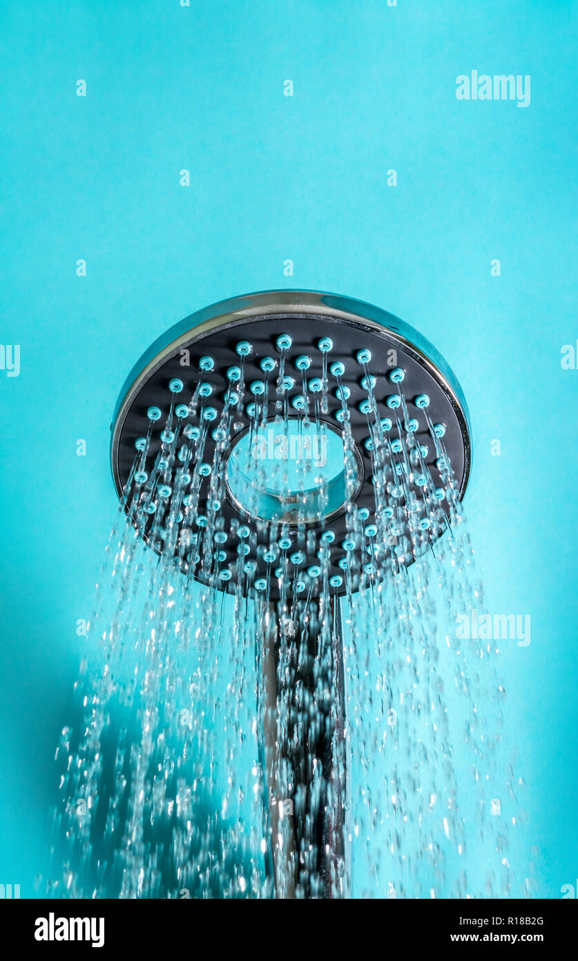 Modern hot shower with stream of water close up on a blue background ...