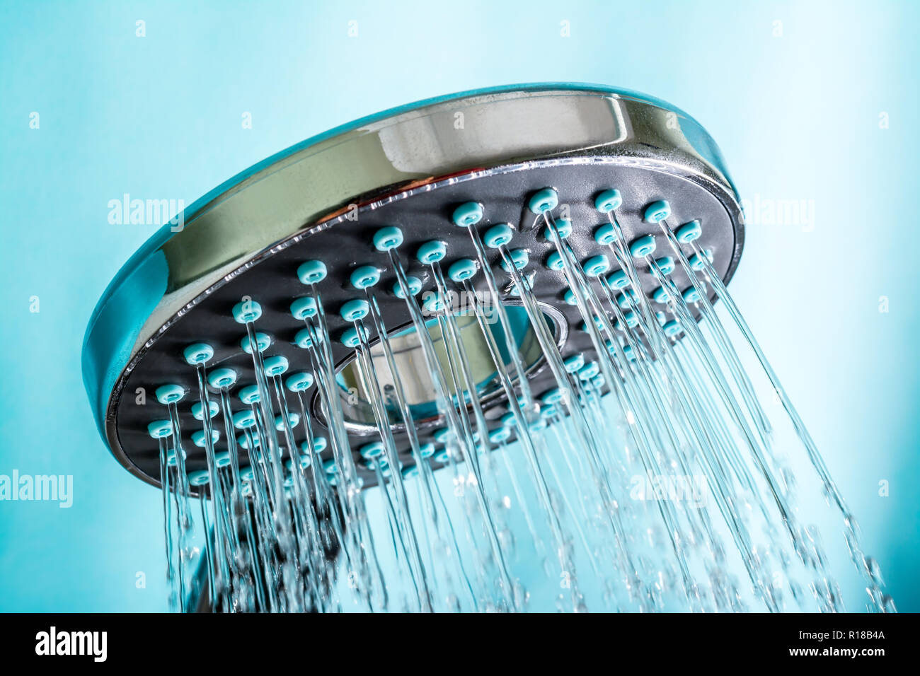 Modern hot shower with stream of water close up on a blue background ...