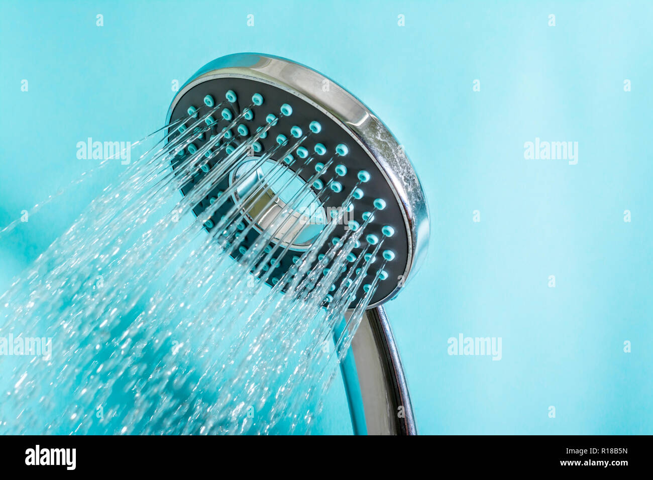 Modern hot shower with stream of water close up on a blue background ...