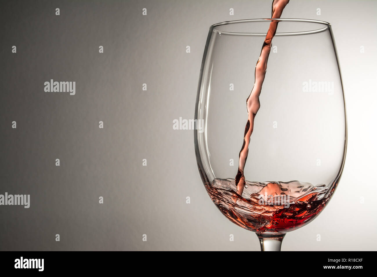 Stream of wine being pouring into a glass close-up, wine splashing in a ...