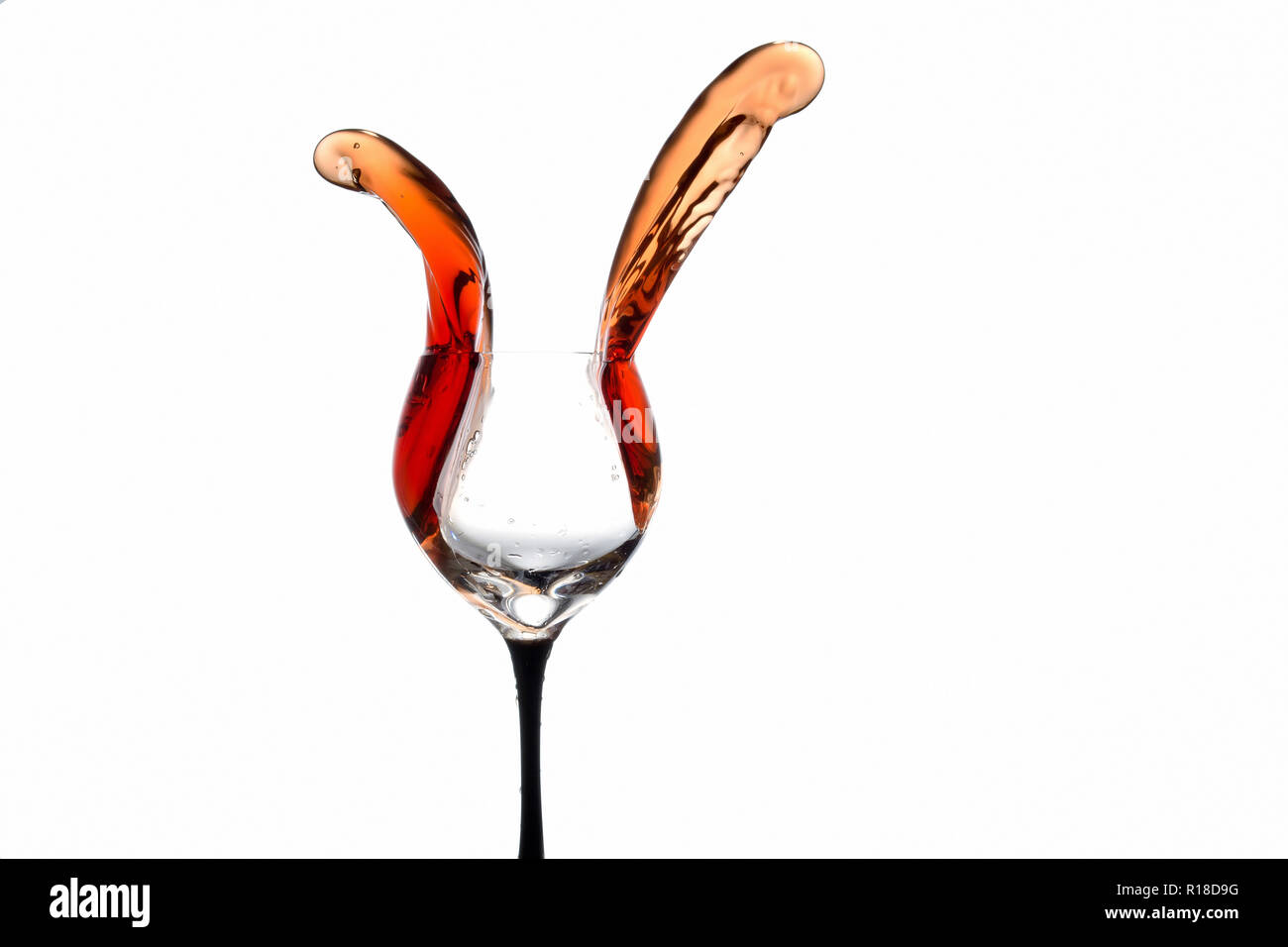 stream of wine being poured out off a glass isolated on a white ...
