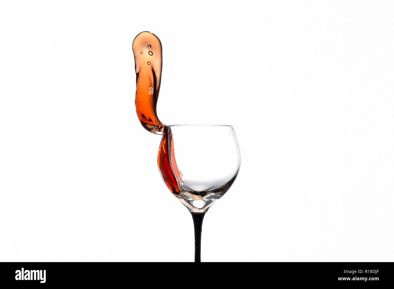 stream of wine being poured out off a glass isolated on a white ...