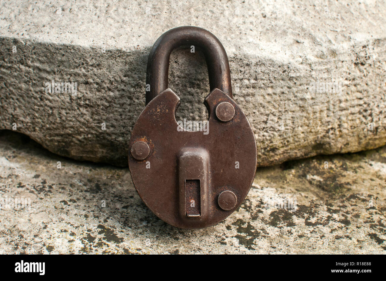 Old weathered grunge retro locked padlock closeup on solid stone ...