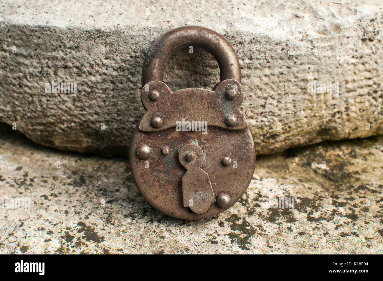 Old weathered grunge retro locked padlock closeup on solid stone ...