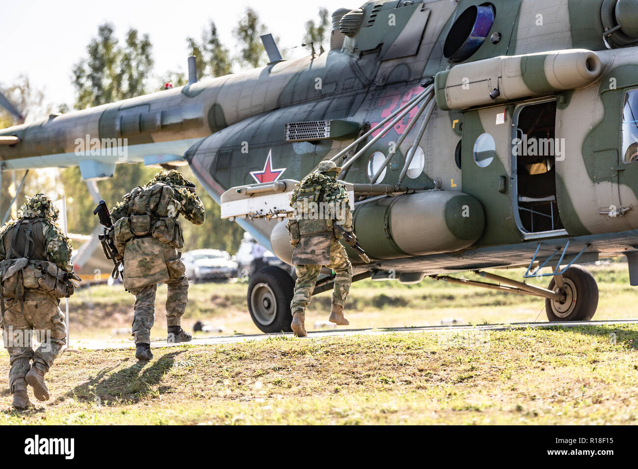 Military helicopter standing on the ground and soldiers loading into it ...