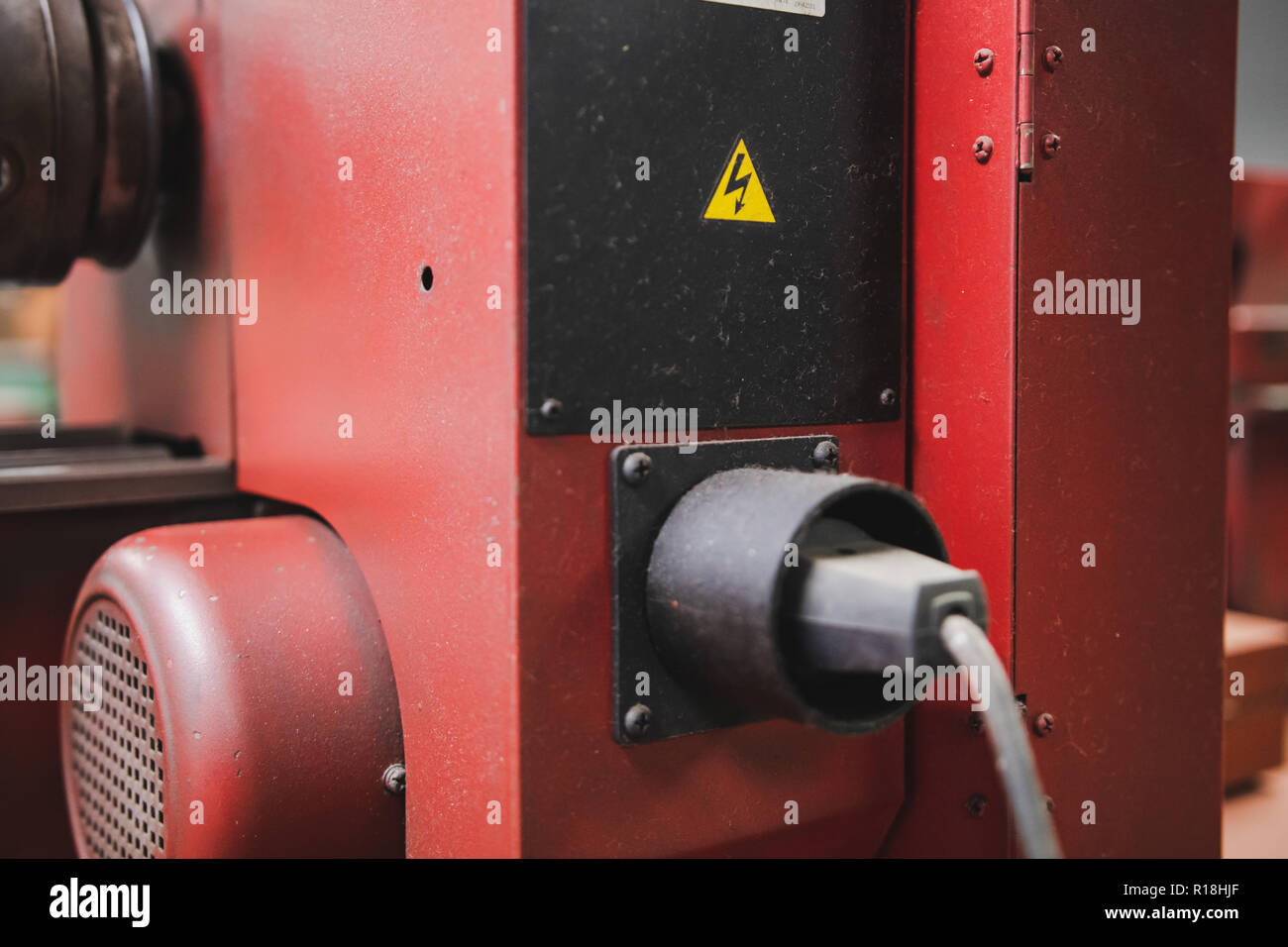 High voltage warning sticker at the back of a power tool in workshop ...