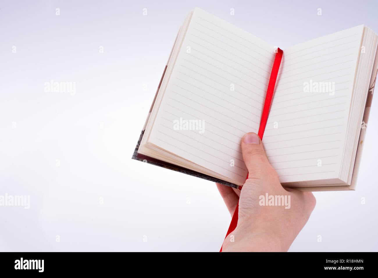 Hand holding a notebook on a white background Stock Photo - Alamy