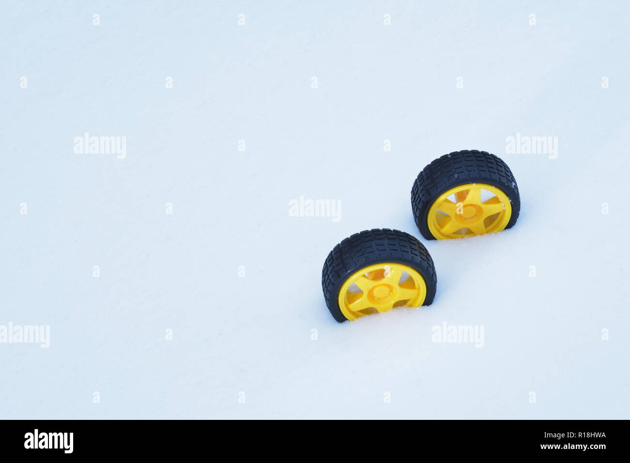 Two small toy or RC model car wheels partially buried in the snow Stock ...