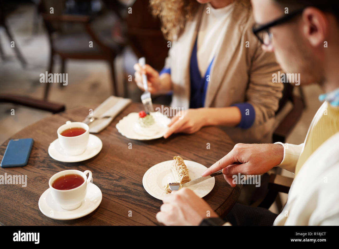 Guy taking piece of dessert from plate while having tea time in ...