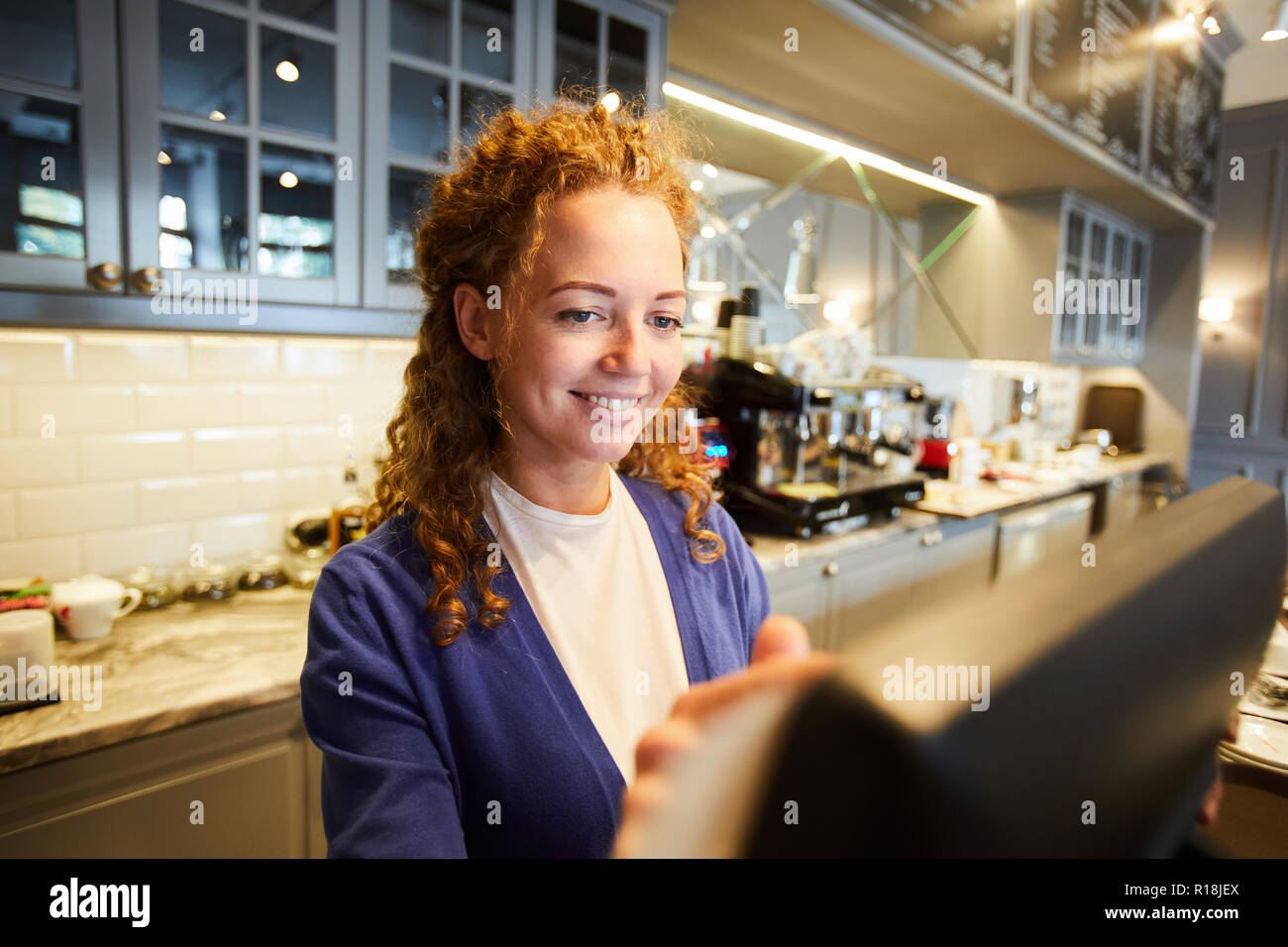 Pretty bar worker standing in front of computer and entering orders of ...