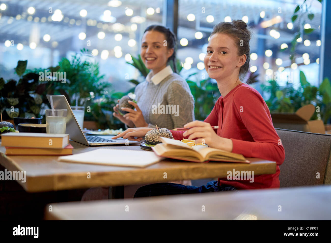 Two happy students sitting by table in college cafe after lessons ...
