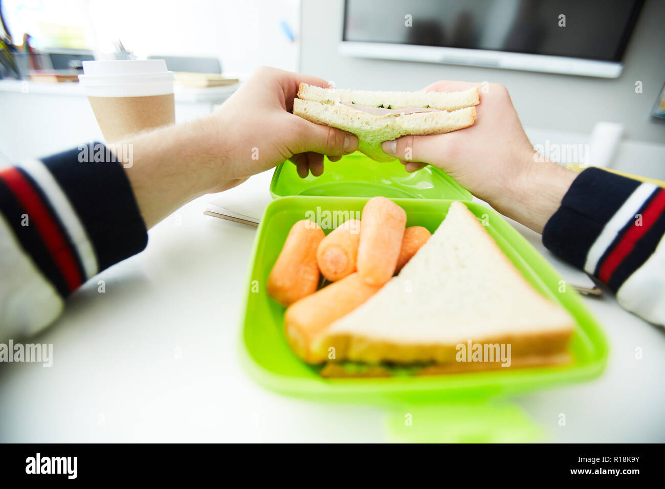 Hands of student holding vegetable sandwich over plastic container with ...
