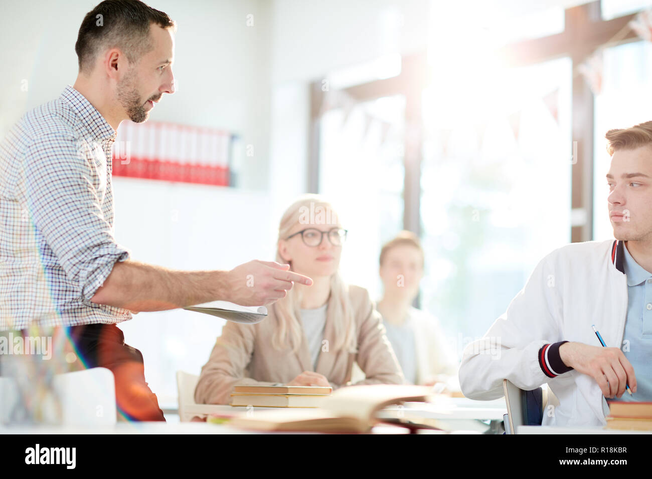 Teacher pointing at one of guys while asking questions to his students ...