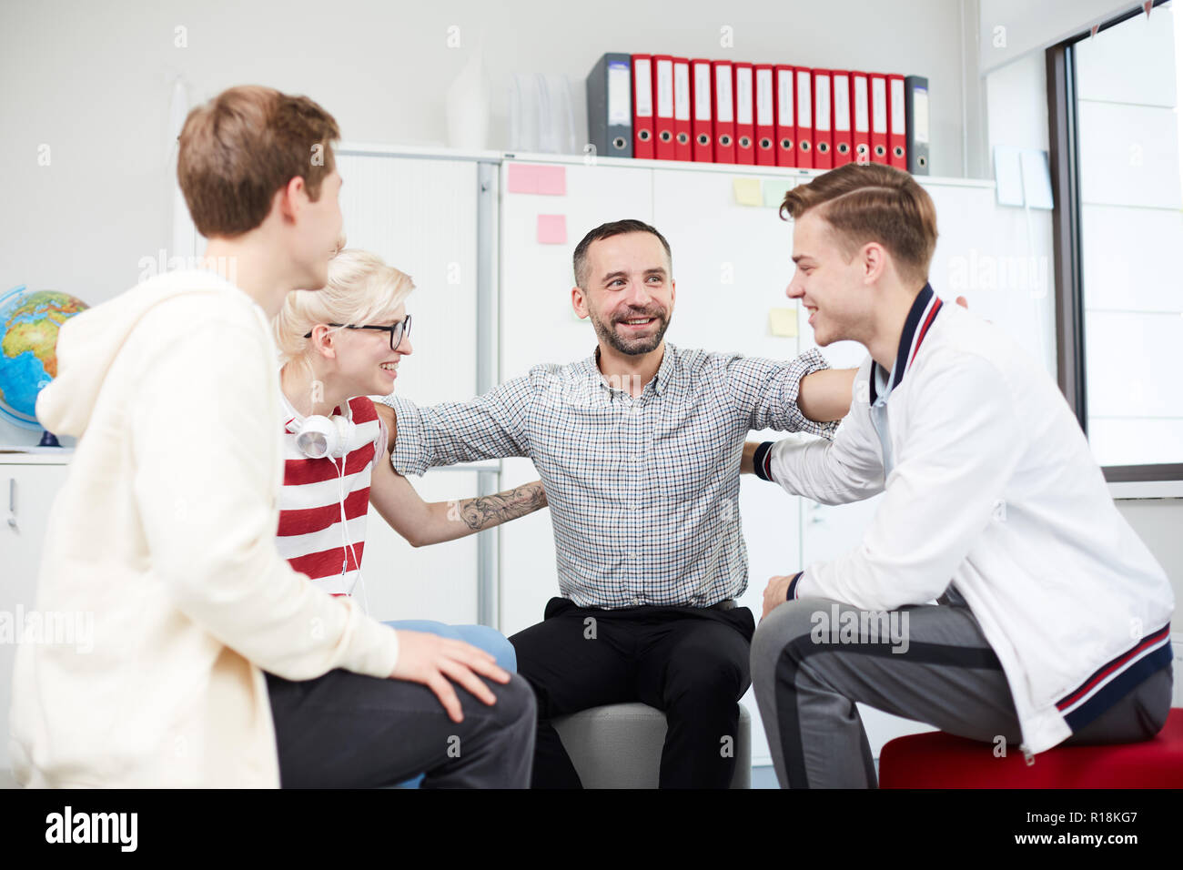 Teacher and students touching each other on back while looking with ...