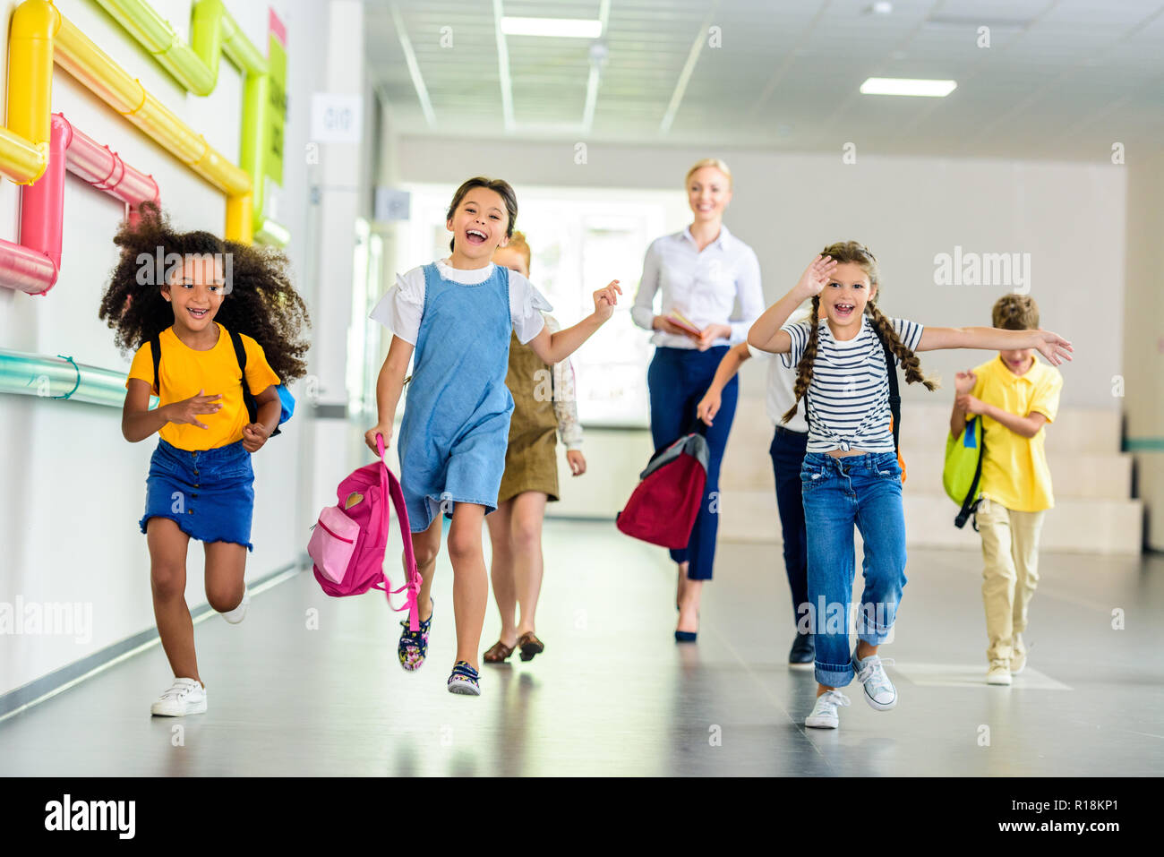 adorable happy schoolchildren running by school corridor together with ...