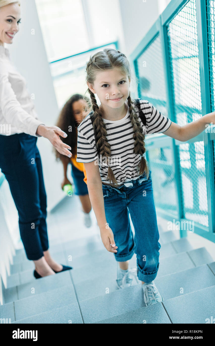 high angle view of schoolgirls going upstairs with teacher at school ...