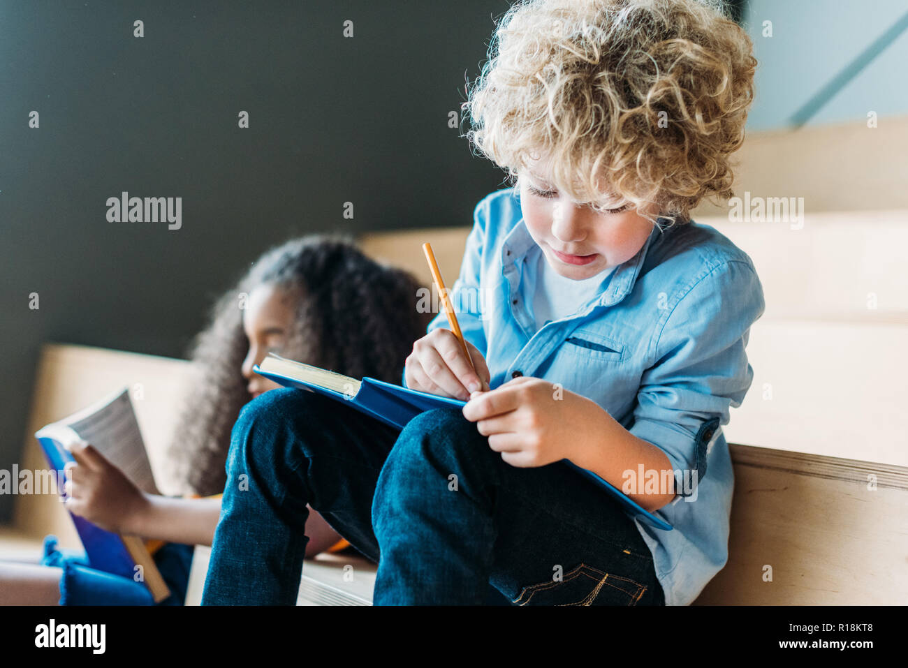 concentrated multiethnic schoolchildren writing in notebooks together ...