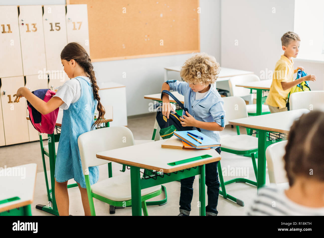 adorable schoolchildren preparing for lesson at classroom Stock Photo ...