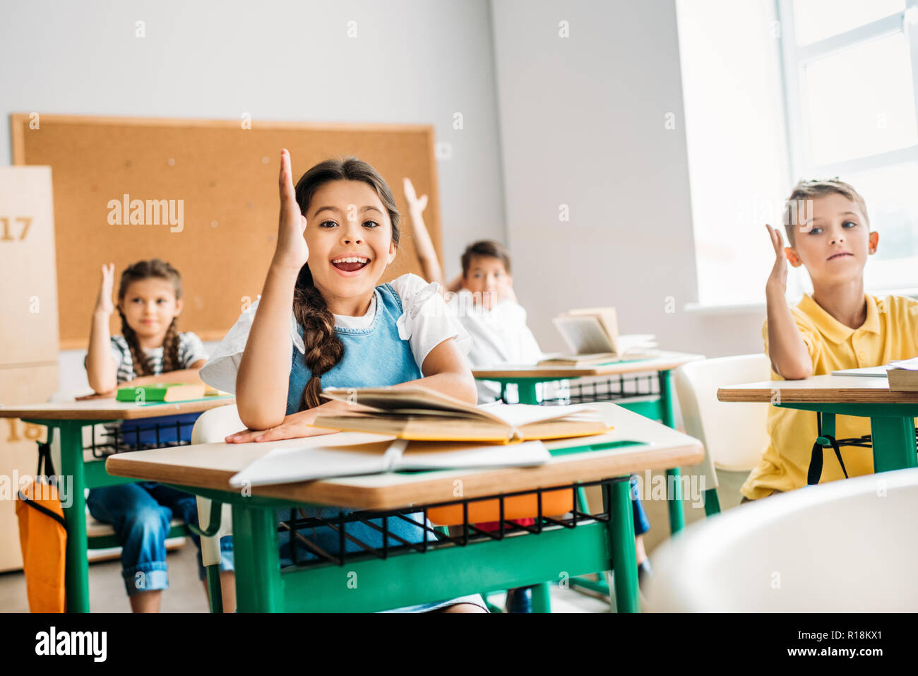 group of pupils raising hands to answer question during lesson Stock ...