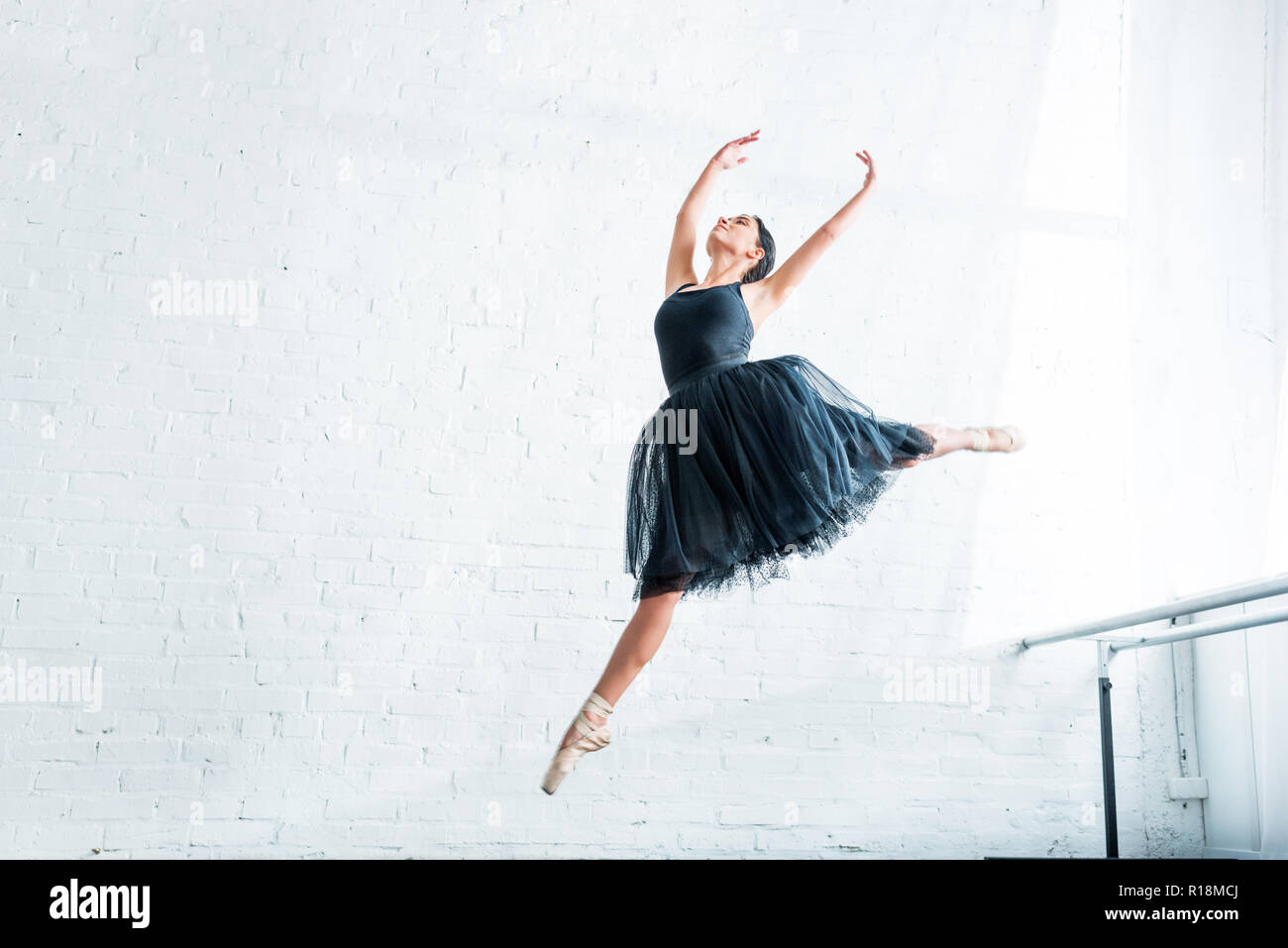 low angle view of beautiful young ballerina dancing in ballet studio ...