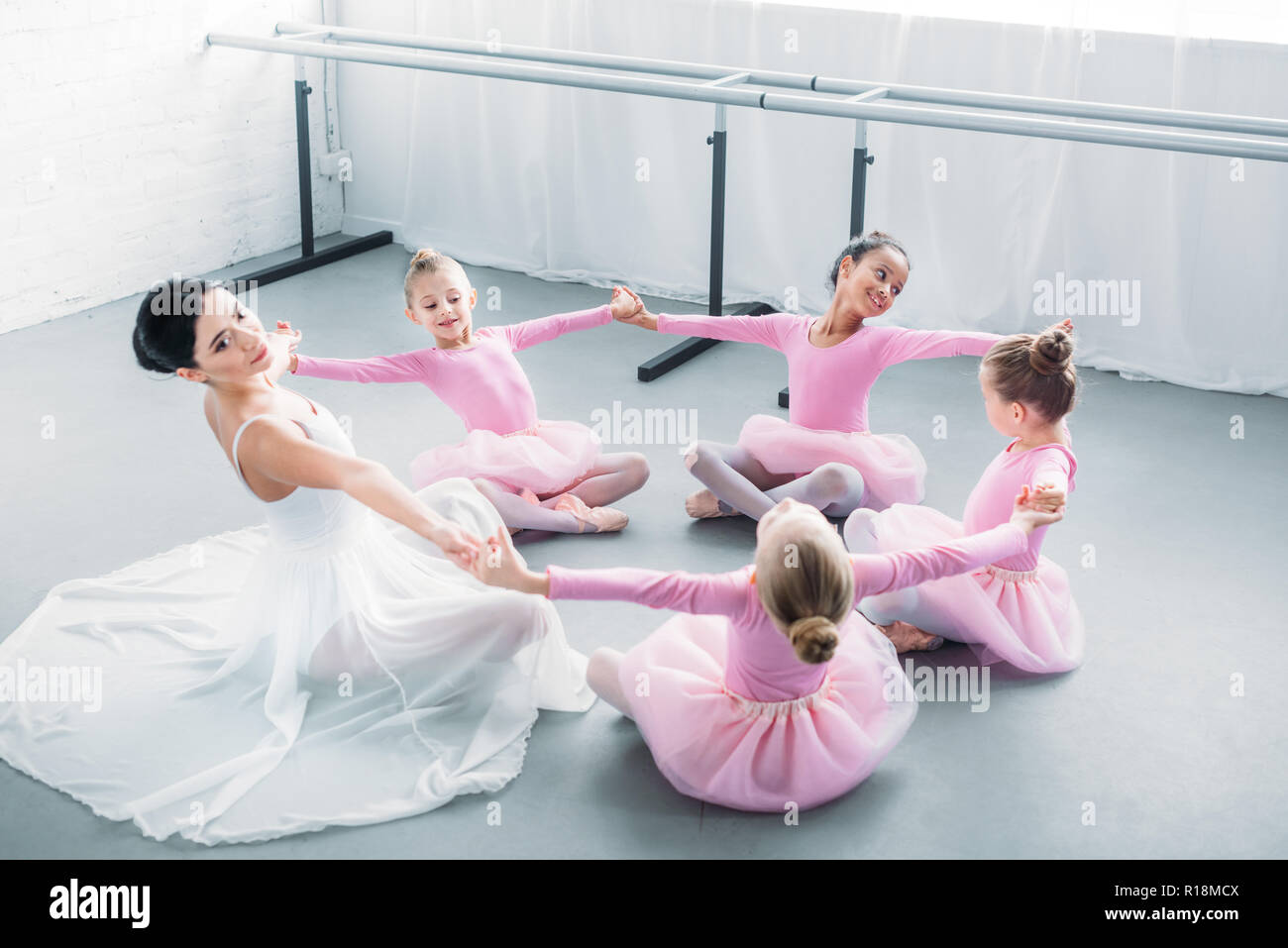 adorable little ballerinas and young teacher practicing together in ballet school Stock Photo ...