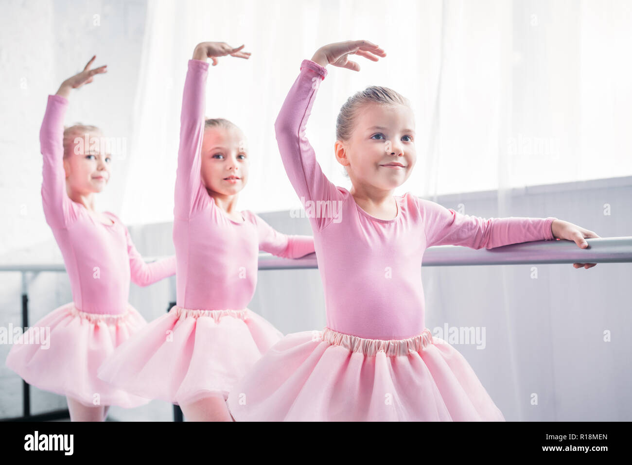 adorable smiling children in pink tutu skirts dancing in ballet studio ...