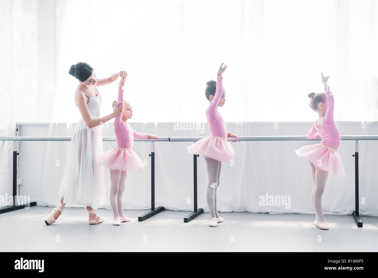 side view of ballet teacher exercising with children in ballet school ...