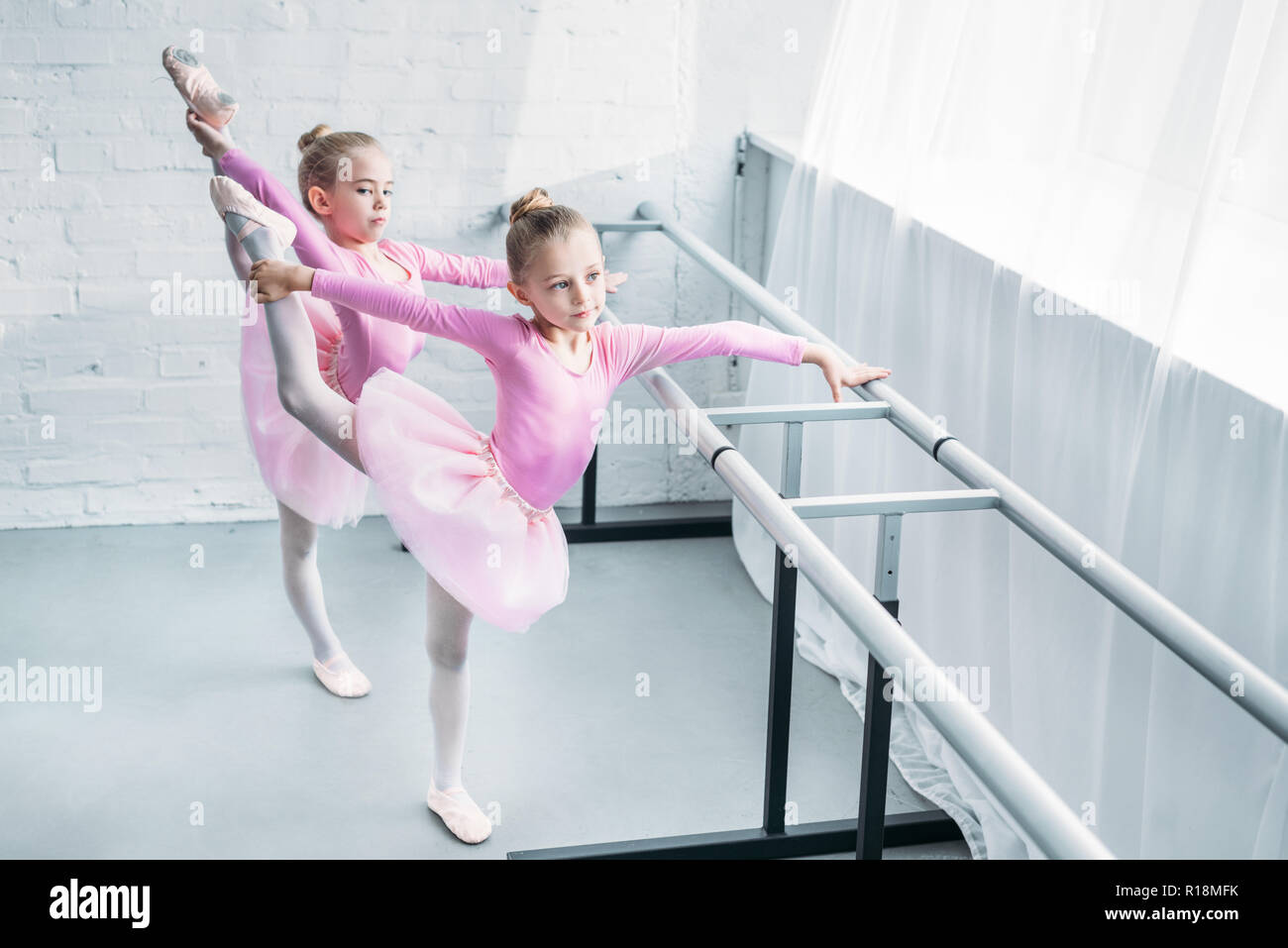 high angle view of cute little ballet dancers stretching in ballet ...