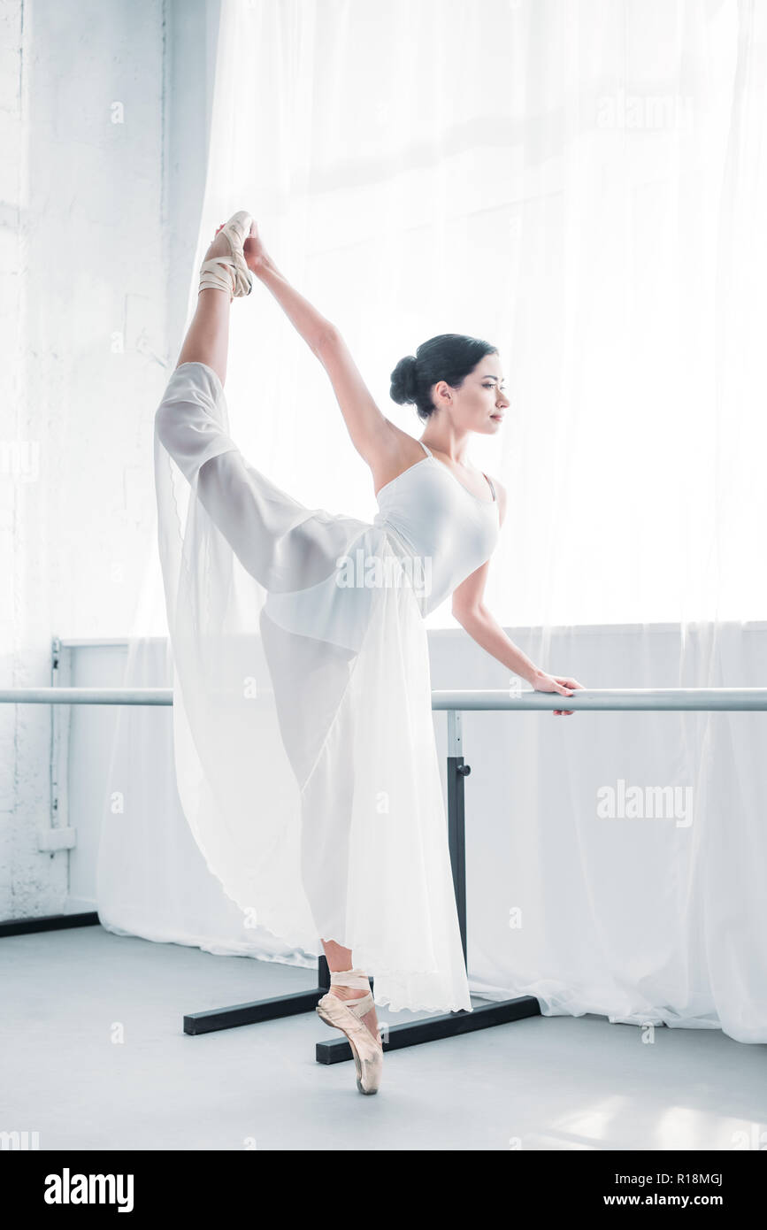 side view of graceful flexible young ballerina practicing ballet in ...