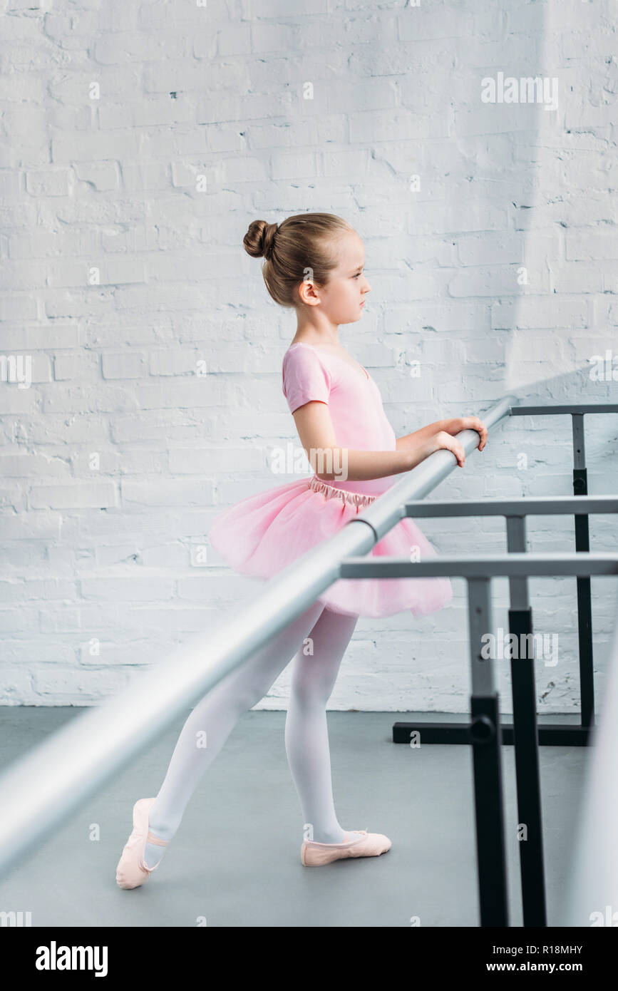 side view of beautiful little ballerina practicing ballet in studio ...