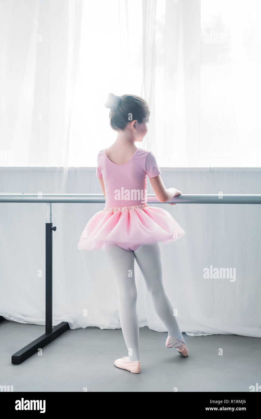 rear view of little kid in pink tutu practicing ballet in ballet school ...