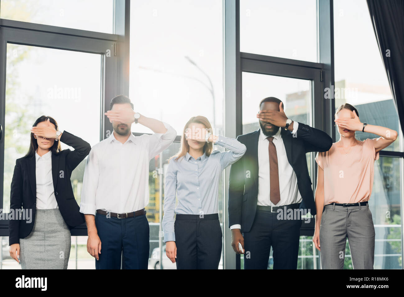 obscured view of multiethnic businesspeople covering eyes in conference ...
