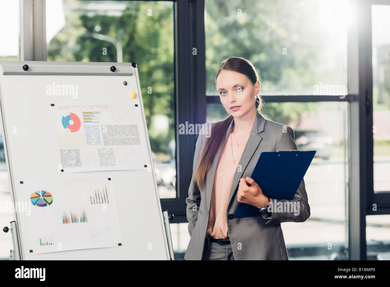 female business speaker with notepad at white board during lecture in ...