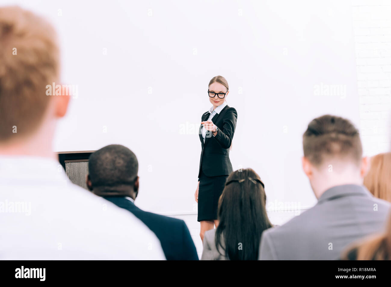 attractive lecturer pointing on multicultural audience during seminar ...