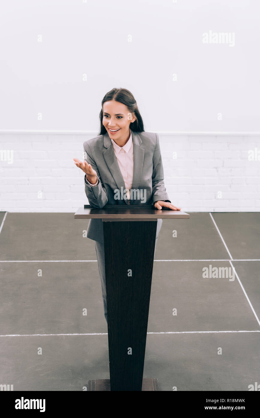 high angle view of attractive smiling lecturer gesturing at podium ...