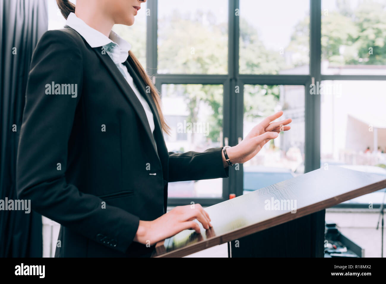 cropped image of lecturer standing and gesturing at podium tribune ...