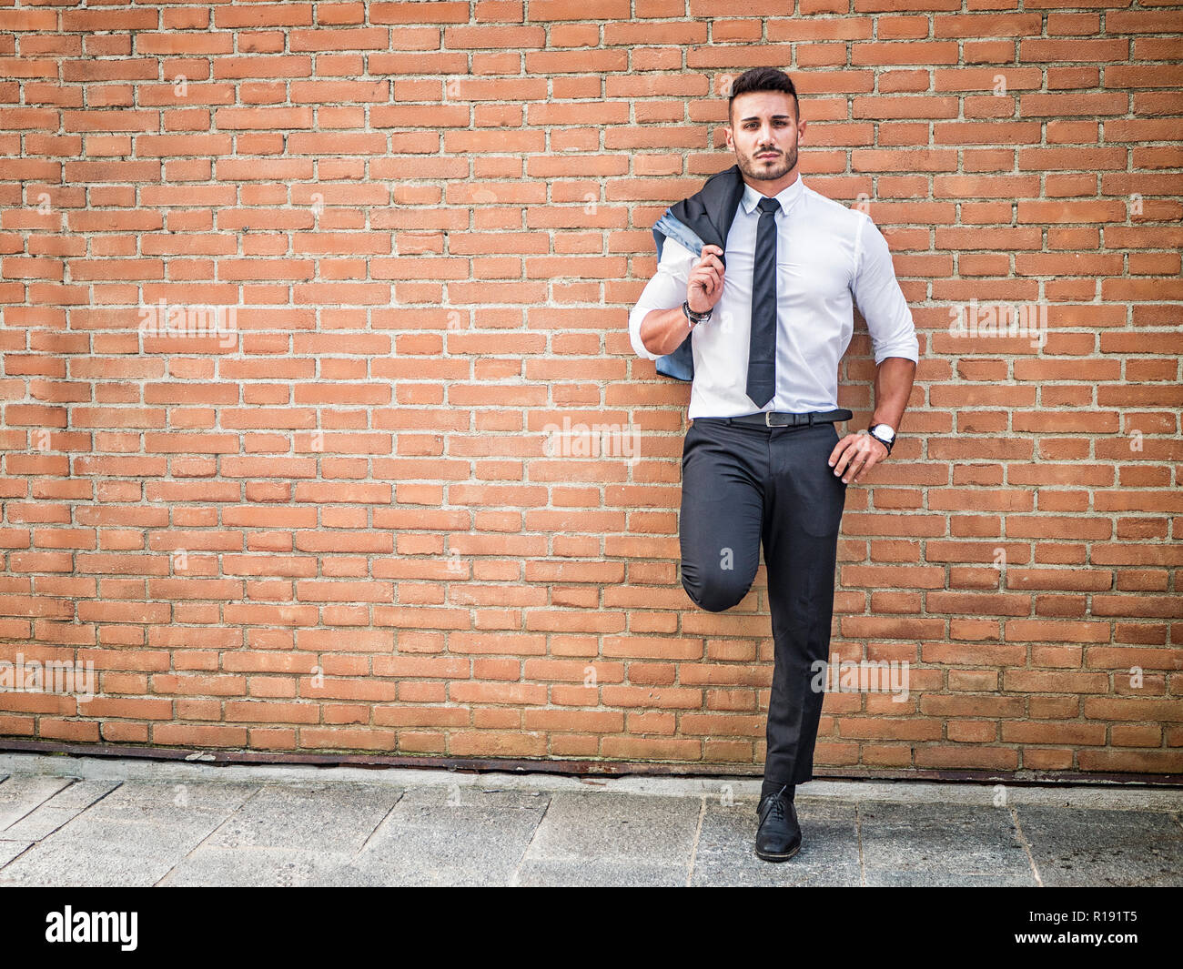 Portrait of stylish young man wearing business suit, standing in modern ...