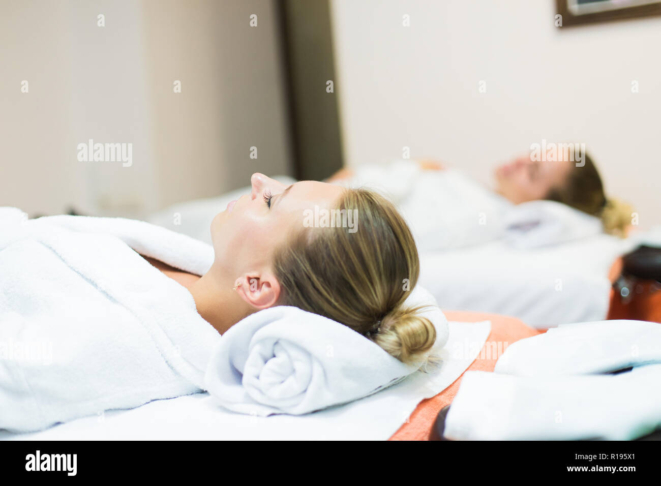 Two cute young women enjoying during a skin care treatment at a spa ...