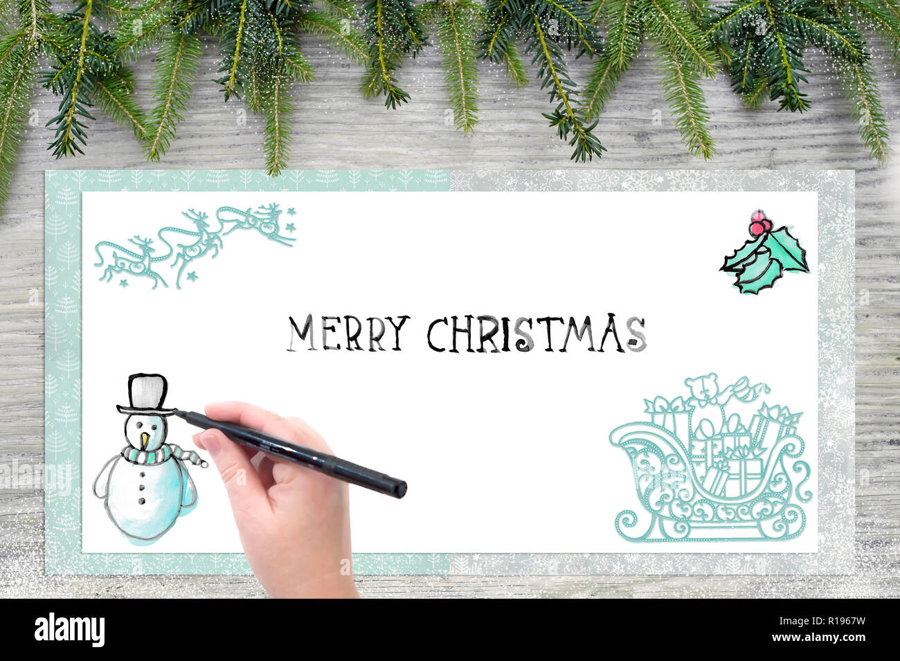 A woman's hand draws Christmas illustrations. English text Merry ...