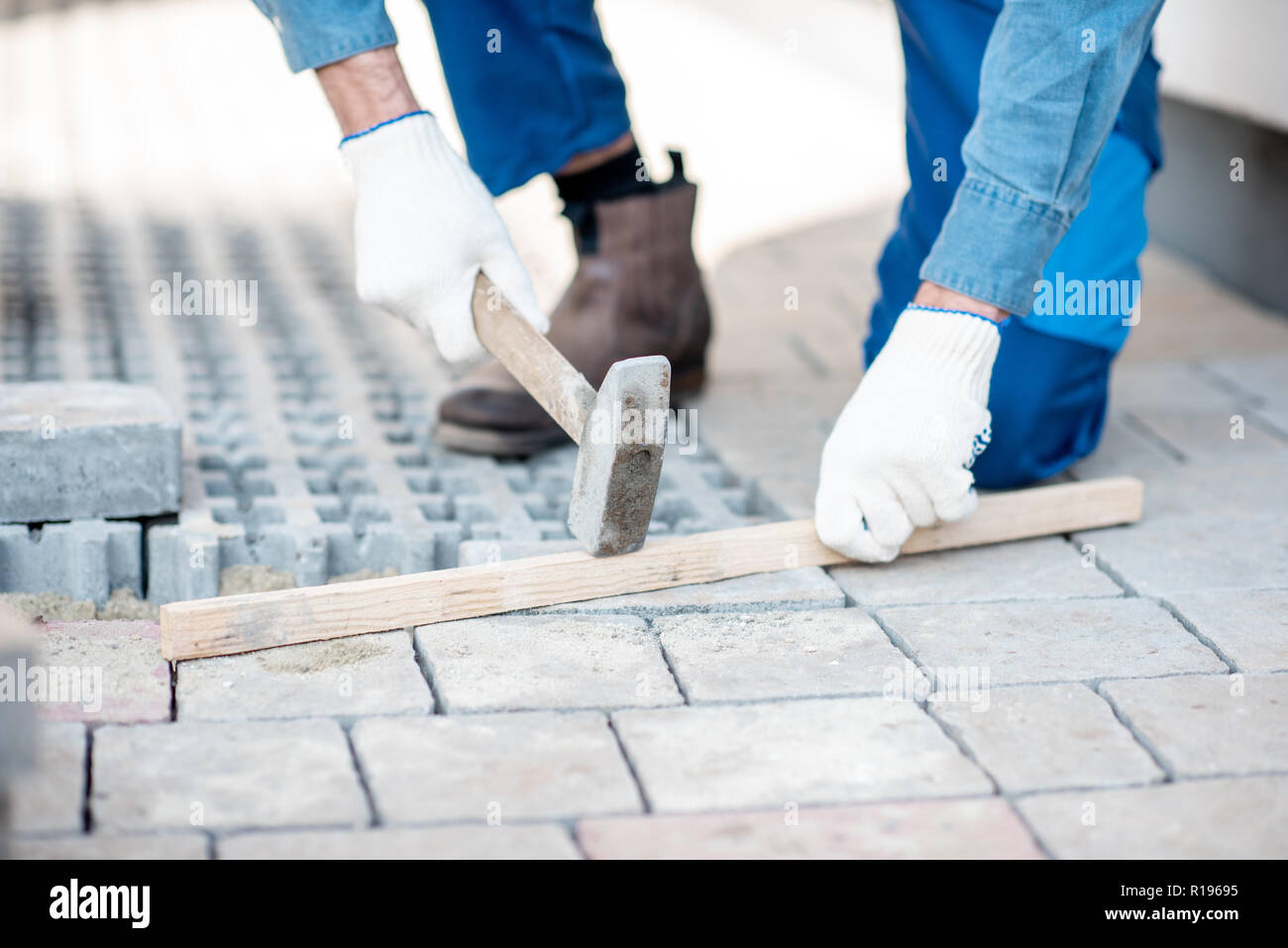 Builder laying paving tiles on the construction site, close-up view ...