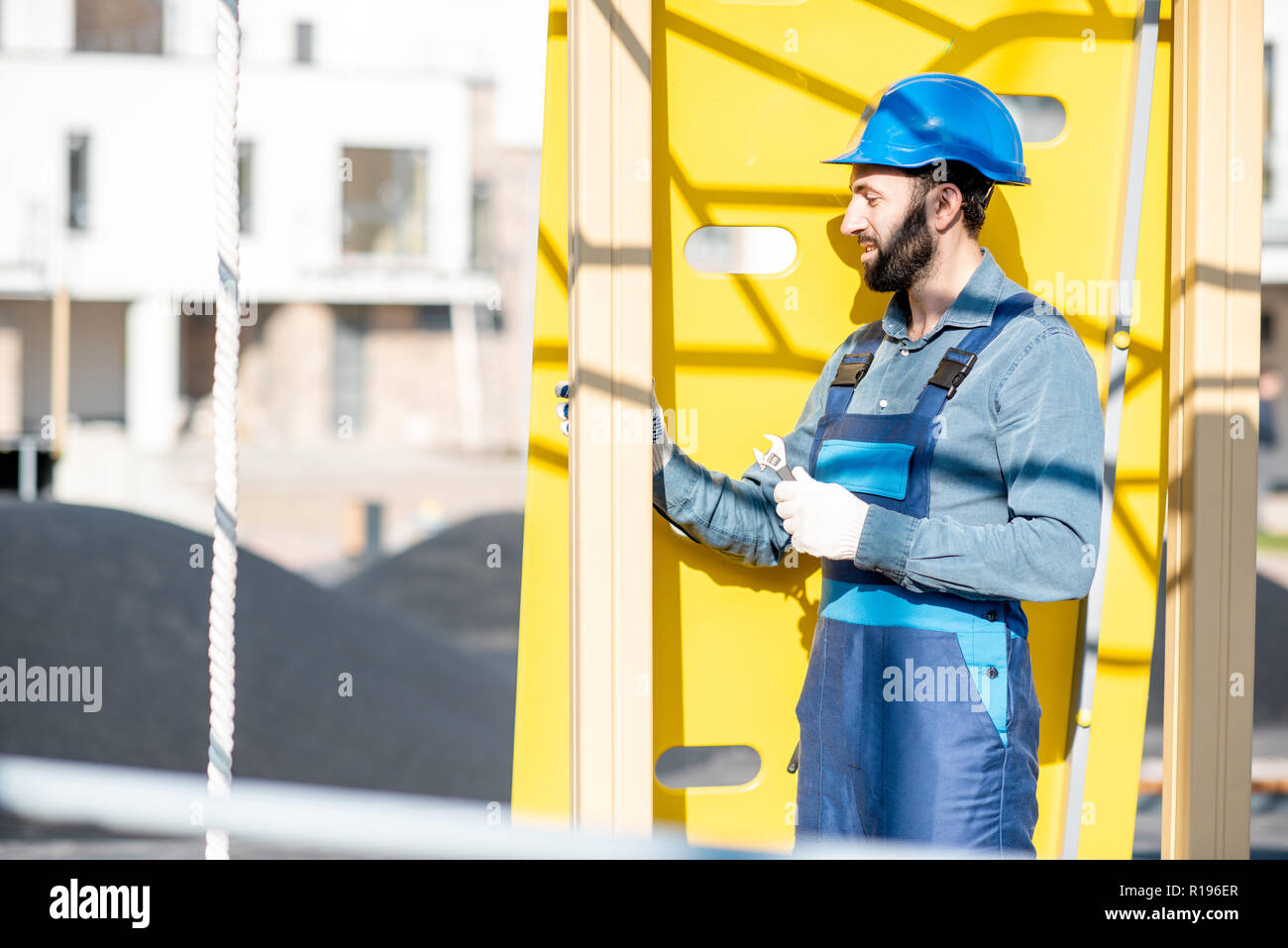 Handsome workman in uniform mounting ladder for kids playing on the ...