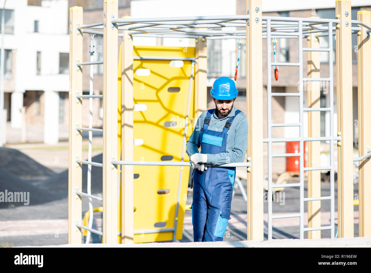 Handsome workman in uniform mounting ladder for kids playing on the ...