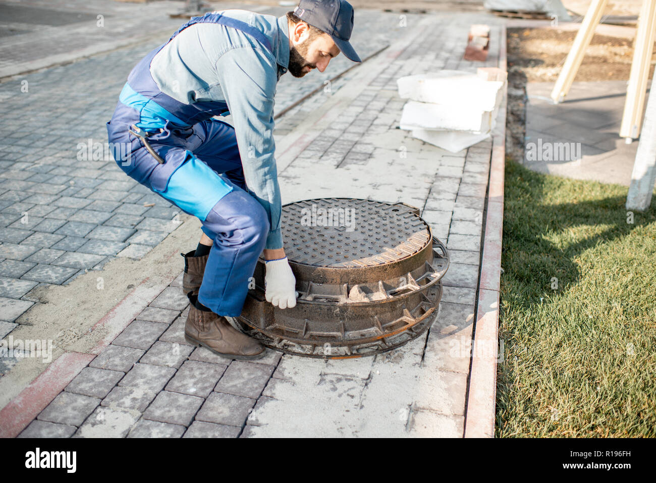 Workman in uniform mounting new road hatches at the residential area ...