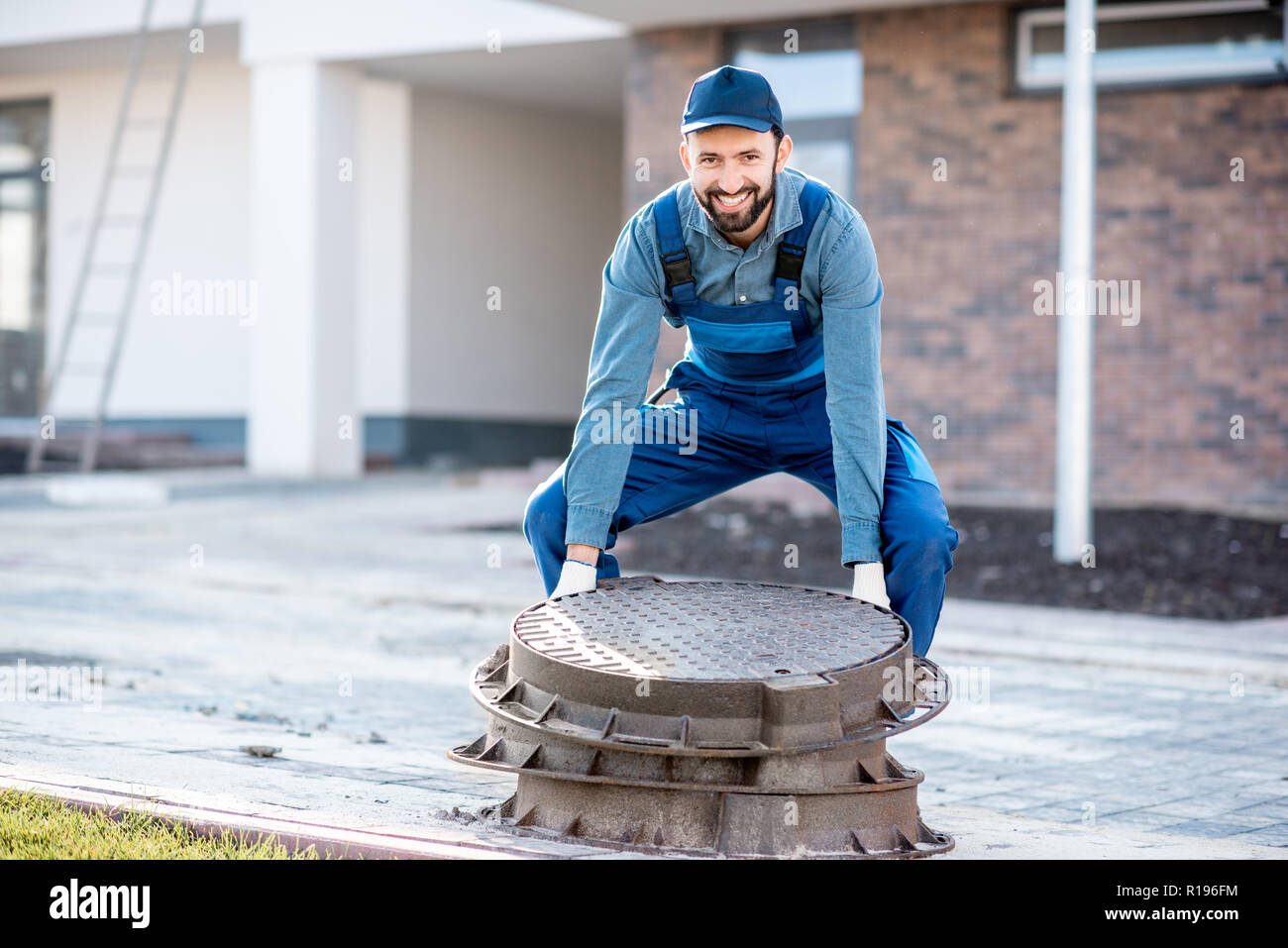 Workman in uniform mounting new road hatches at the residential area ...