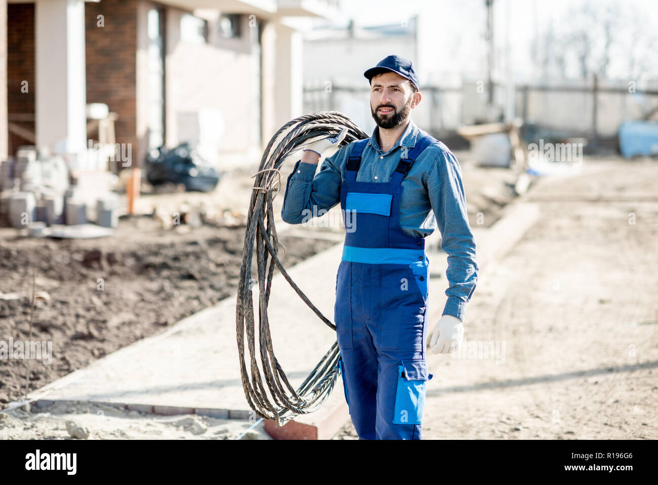 Portrait of a handsome electrician in uniform with power cable for the ...