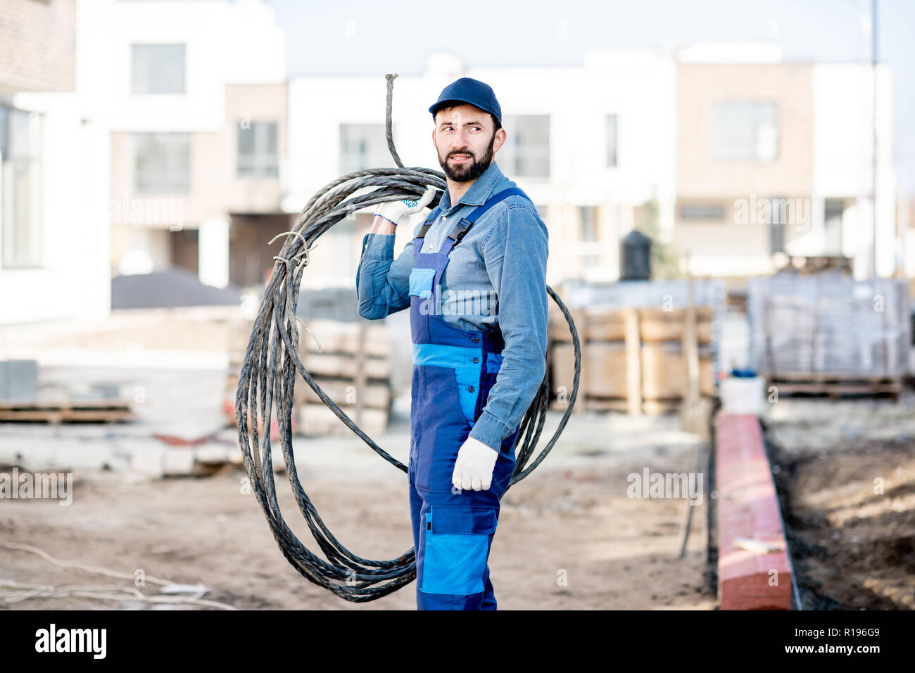 Portrait of a handsome electrician in uniform with power cable for the ...