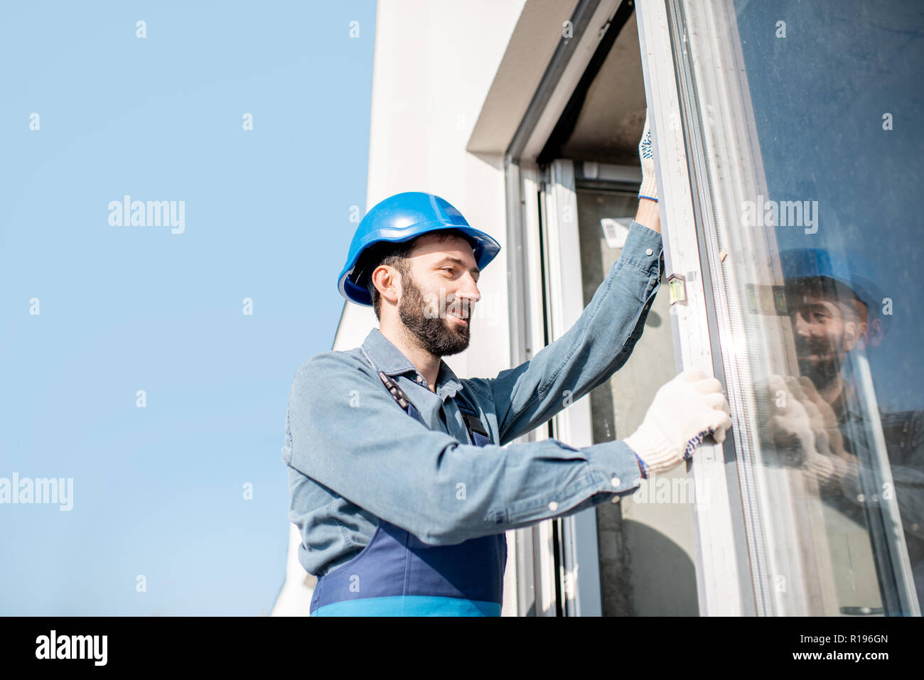 Workman in uniform mounting windows checking the level on the white ...