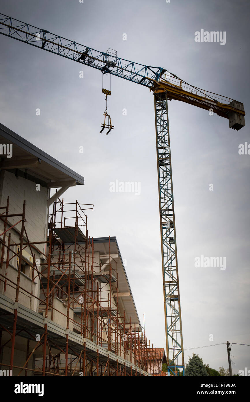 tower crane in a residential construction site with grey sky. Vertical ...