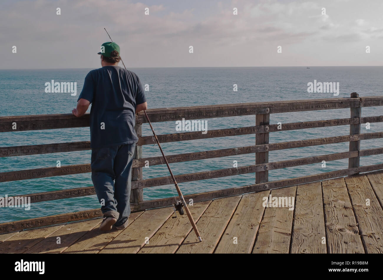 A man fishing from a pier above the Pacific ocean in Oceanside ...
