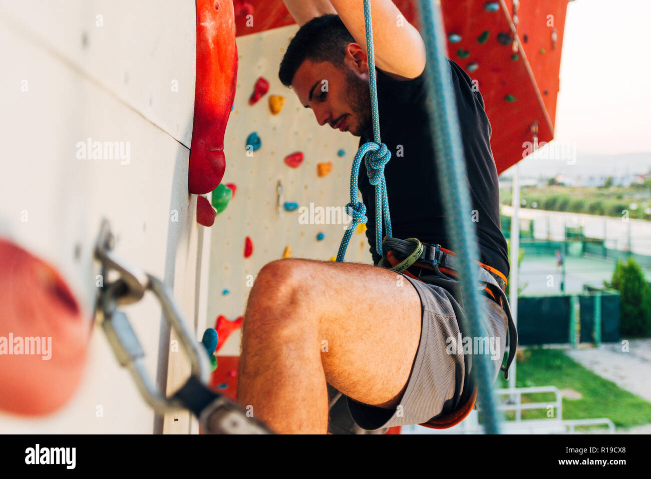 Young climber guy climbing on practical rock in climbing center ...